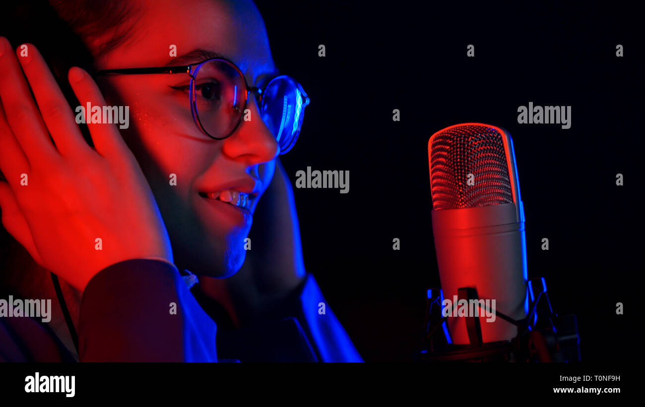 A young woman singing in neon lighting in the studio Stock Photo - Alamy