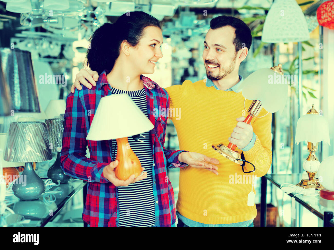Smiling positive man and girl in lighter shop choose desk lamp for ...