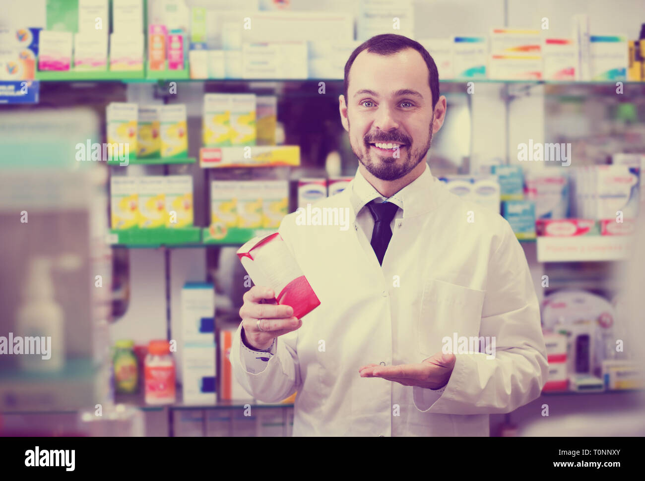 Positive male pharmacist offering reliable medicaments in drugstore ...