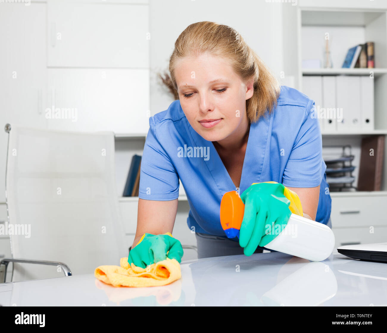 Positive female worker janitor in uniform cleaning desk in office Stock ...