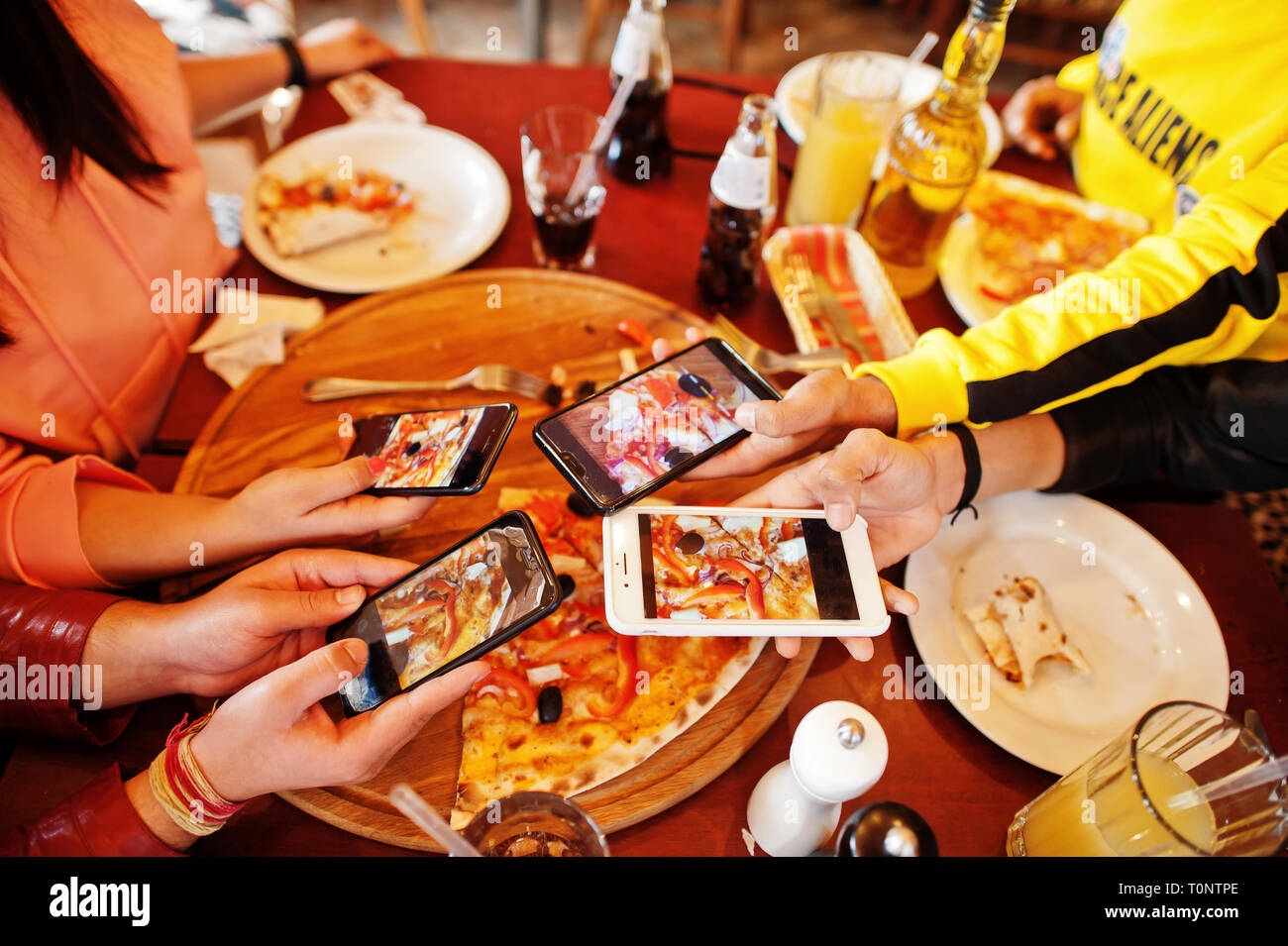 Hands of friends making photo by phones of pizza during party at ...