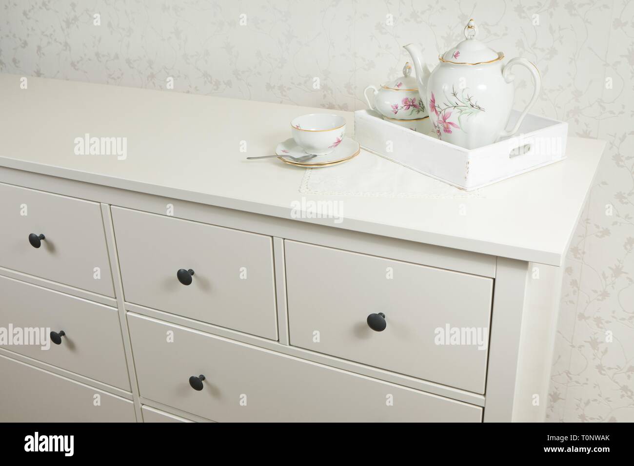 White tea service on white commode ready for use in bedroom on tray ...