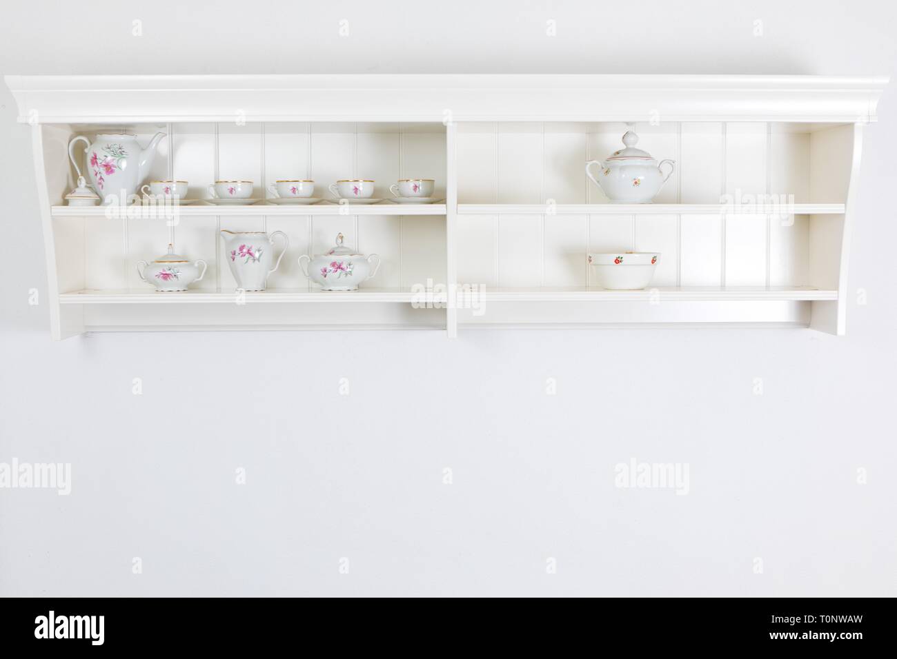White tea shelf with mugs.Tea dish on the wall. White wall with free ...