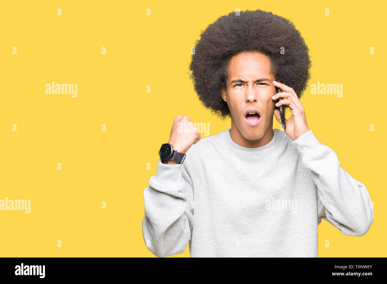 Young african american man with afro hair talking on smartphone annoyed ...