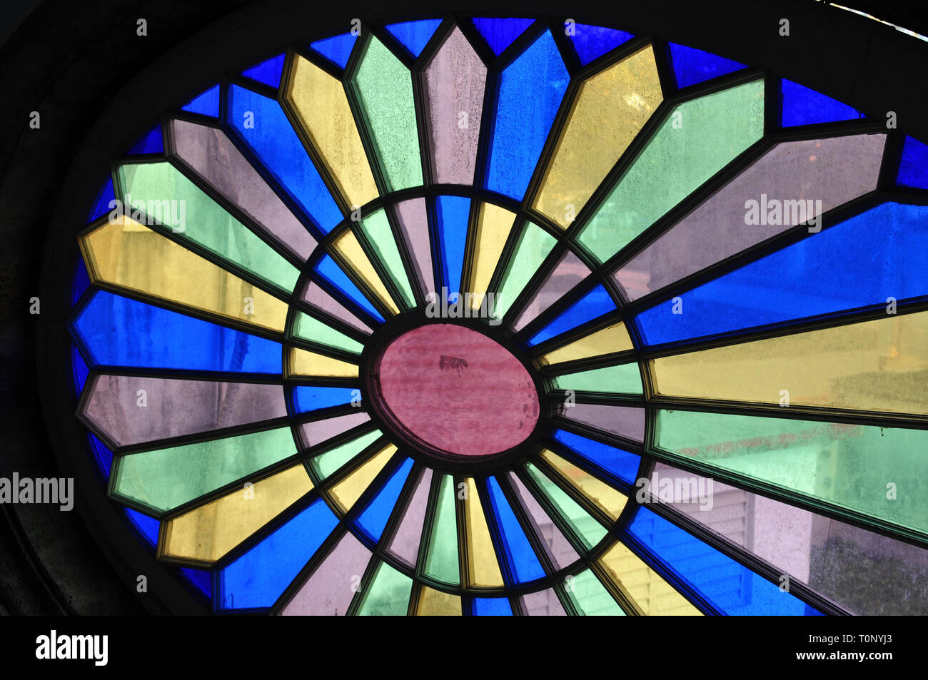 A colorful round stained glass window installed in an historic building ...