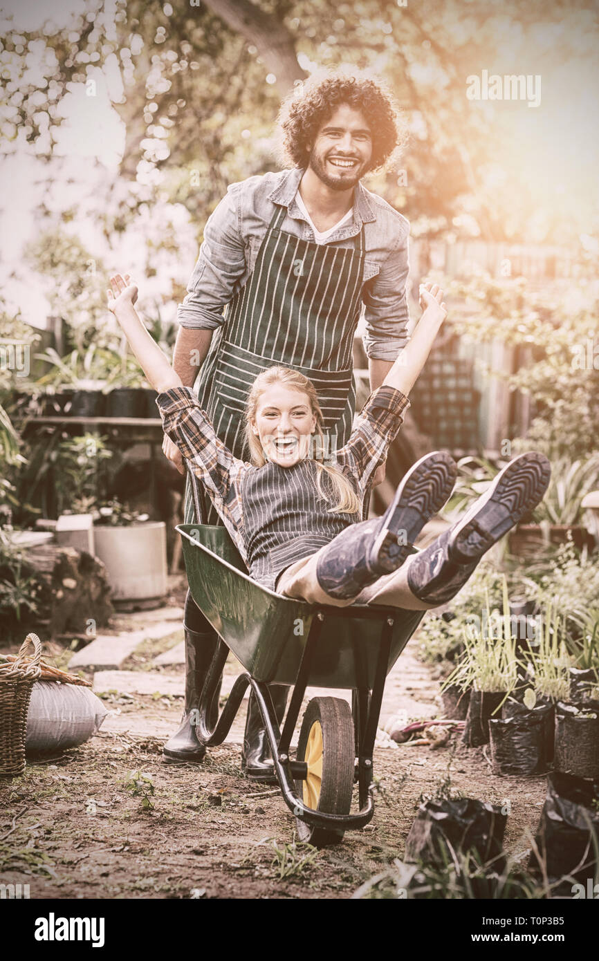 Cheerful man giving wheelbarrow ride to female gardener Stock Photo - Alamy