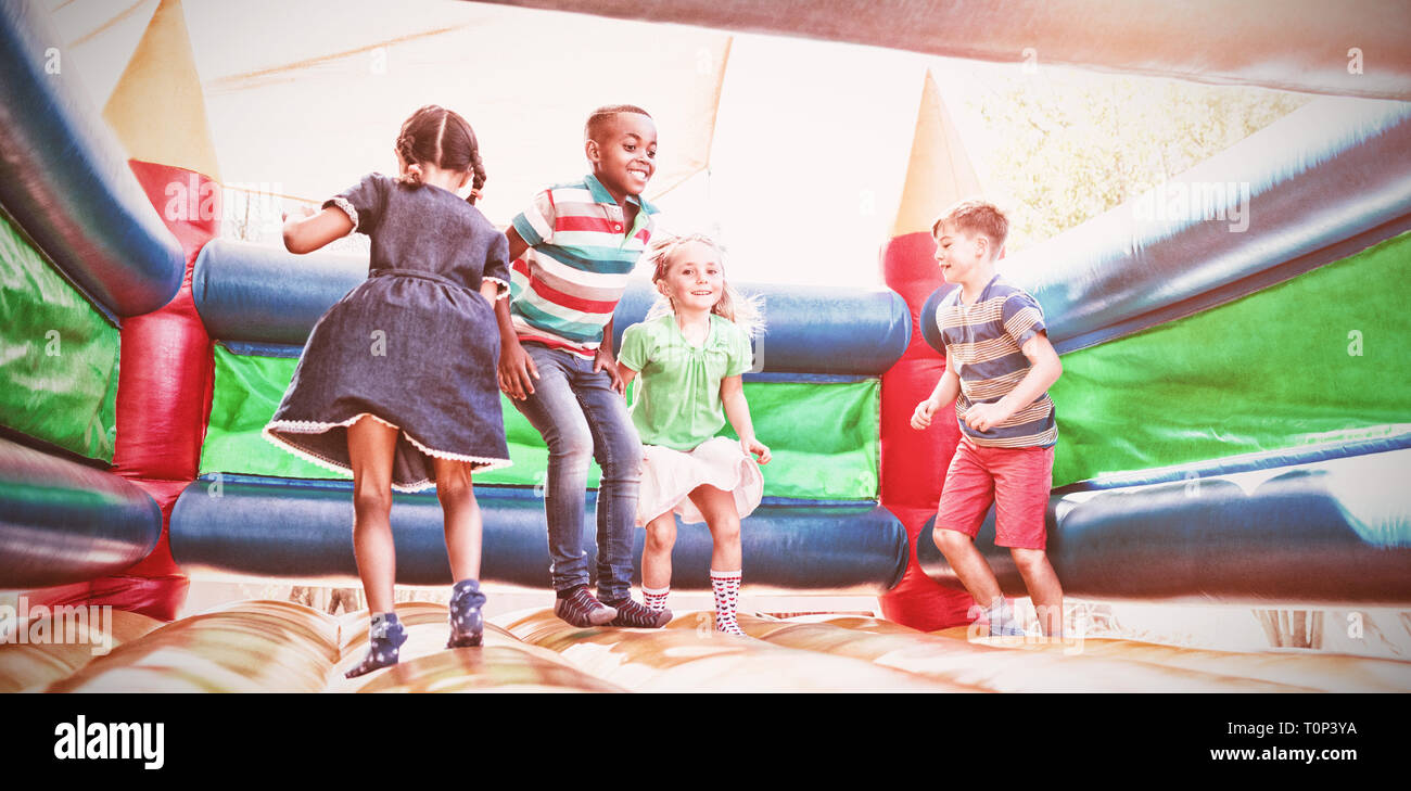 Friends playing on bouncy castle at playground Stock Photo - Alamy