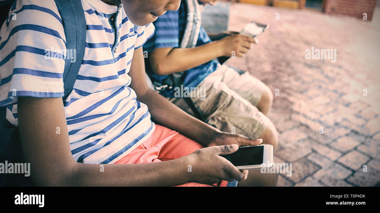 Schoolboys using mobile phones at corridor in school Stock Photo - Alamy