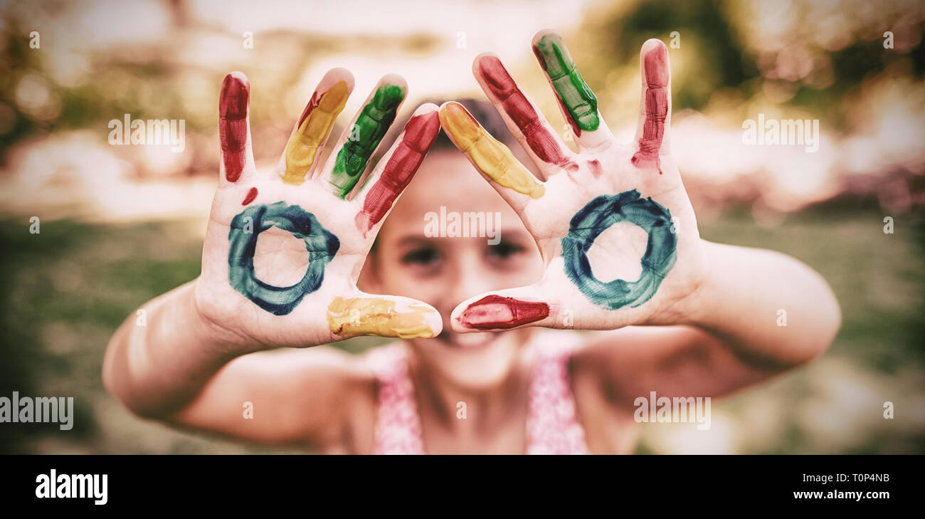 Little girl making a triangle with her painted hands to the camera ...