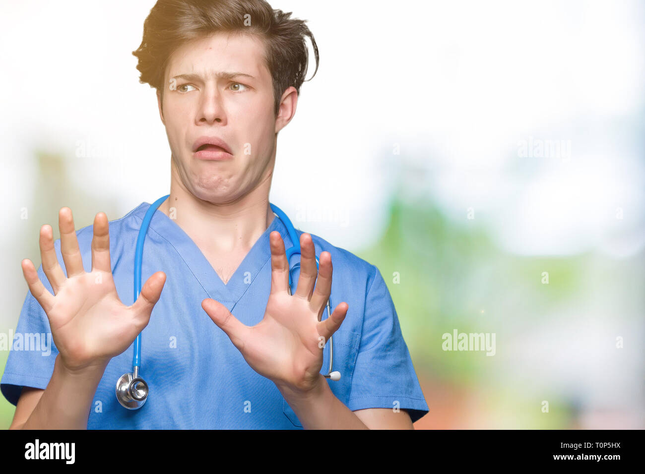Young doctor wearing medical uniform over isolated background afraid ...