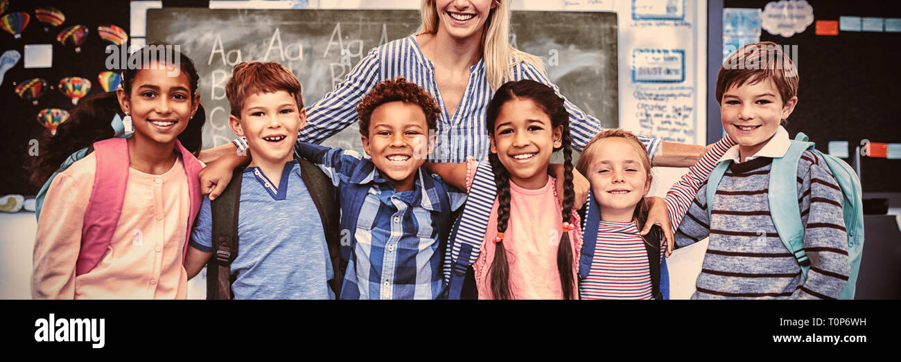 Happy teacher standing with schoolkids in classroom Stock Photo - Alamy