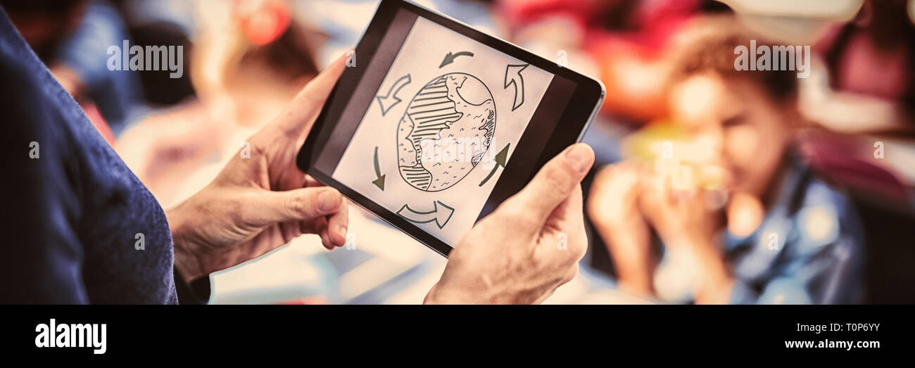 Teacher using digital tablet while teaching in classroom Stock Photo ...