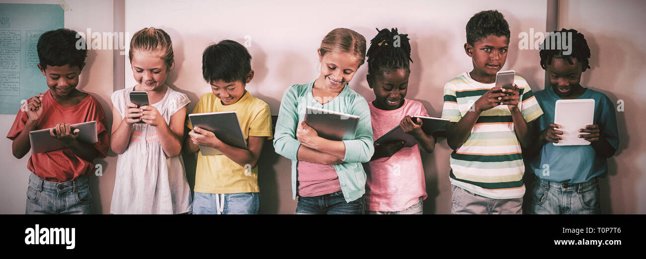 Happy pupils standing with technology Stock Photo - Alamy