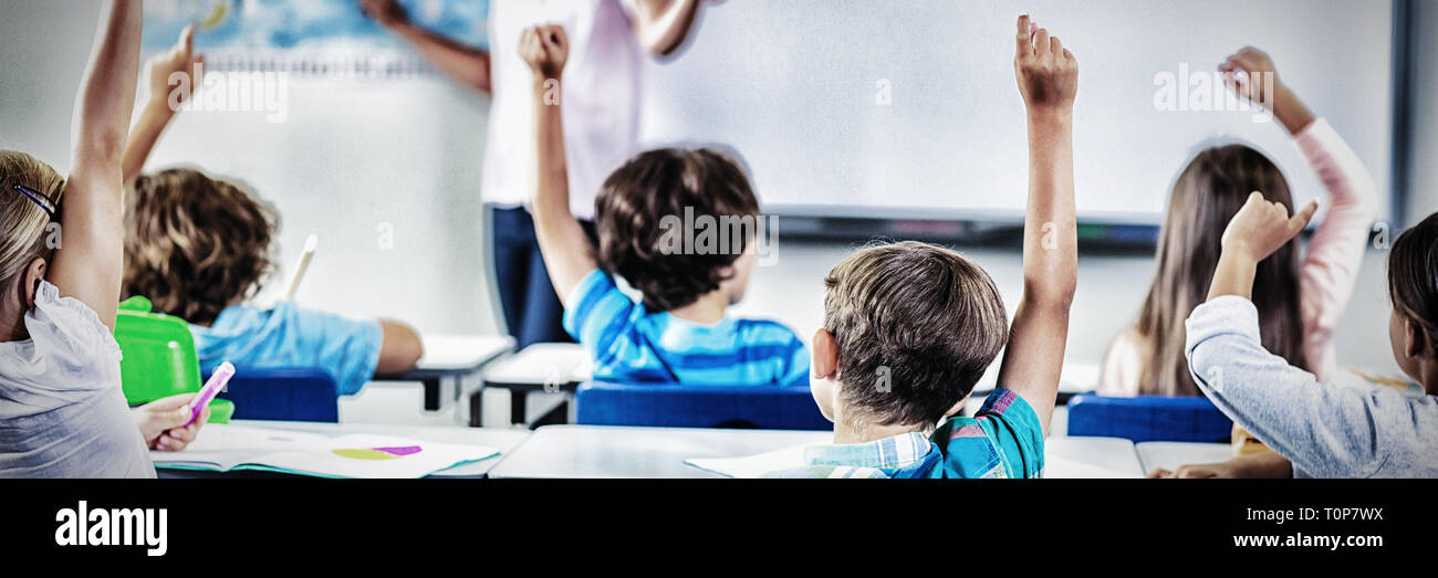 Kids raising hand in classroom Stock Photo - Alamy