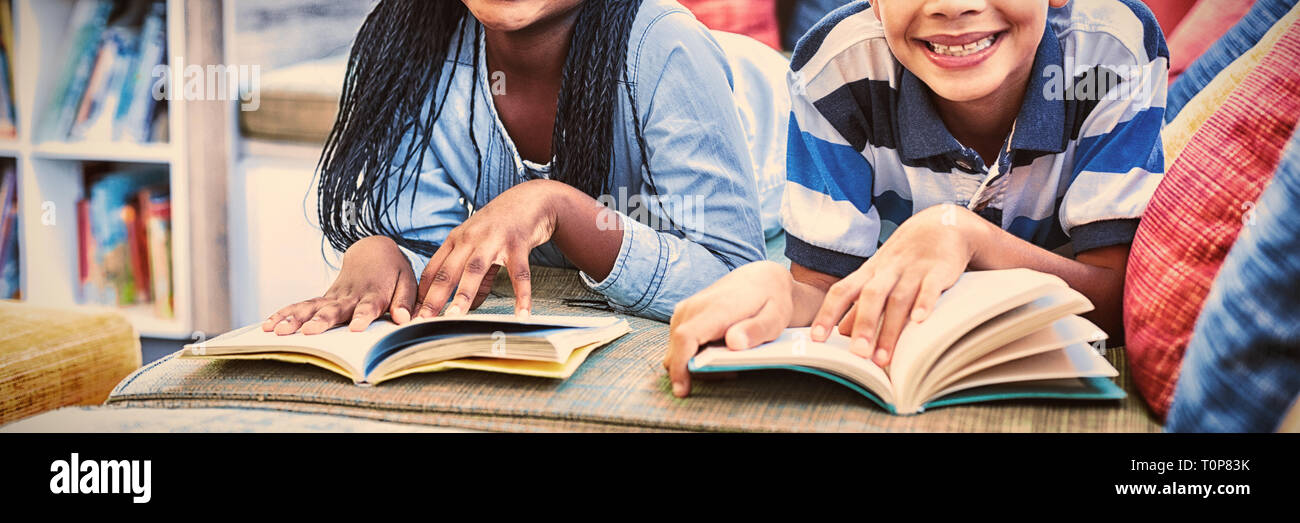 School kids lying on sofa and reading book Stock Photo - Alamy