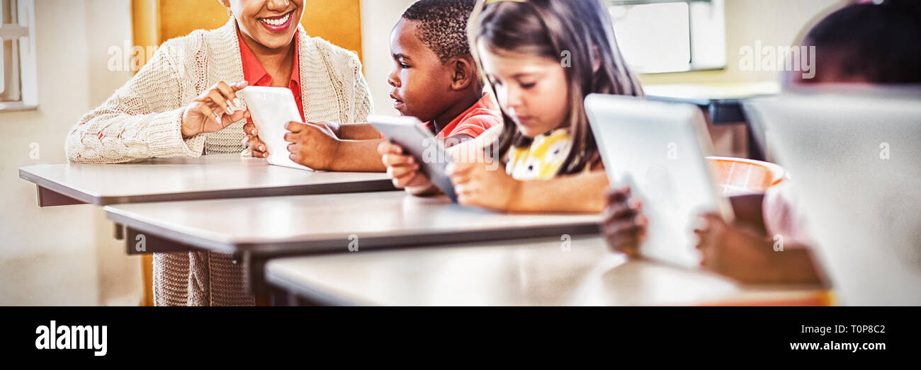 Teacher giving lesson to her students with technology Stock Photo - Alamy