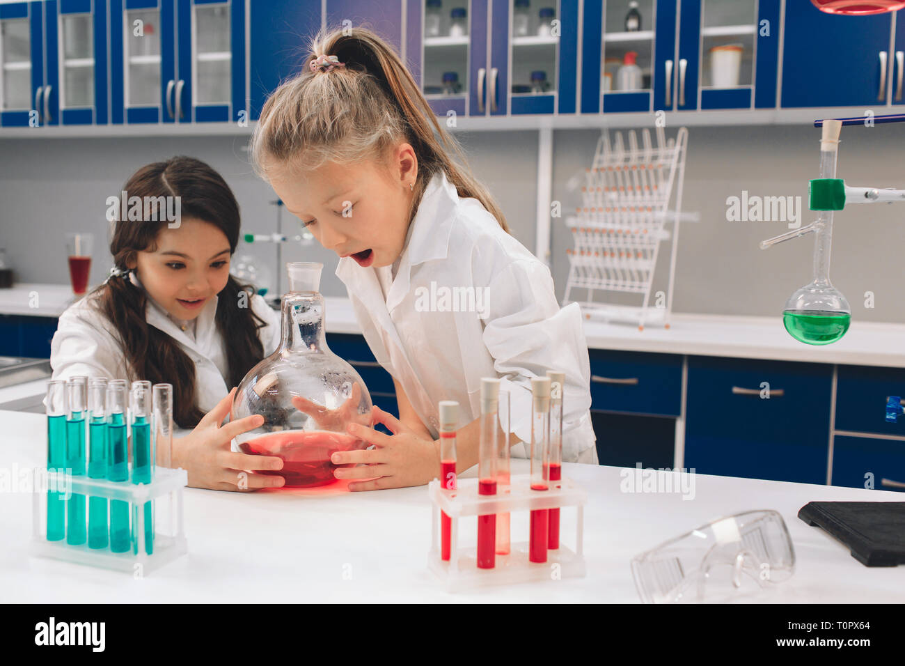 Two little kids in lab coat learning chemistry in school laboratory ...
