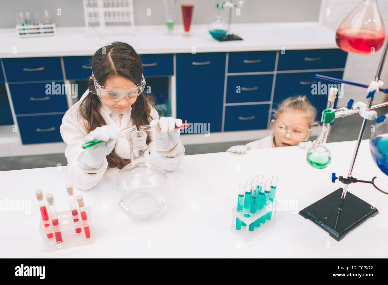 Two little kids in lab coat learning chemistry in school laboratory ...