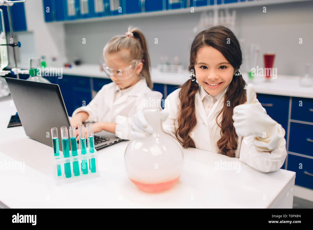 Two little kids in lab coat learning chemistry in school laboratory ...