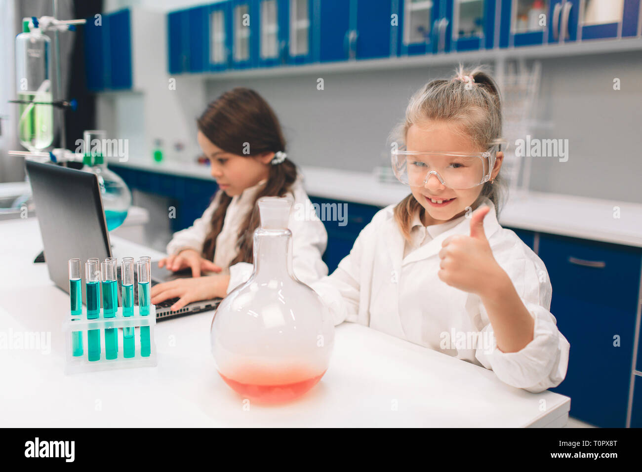 Two little kids in lab coat learning chemistry in school laboratory ...