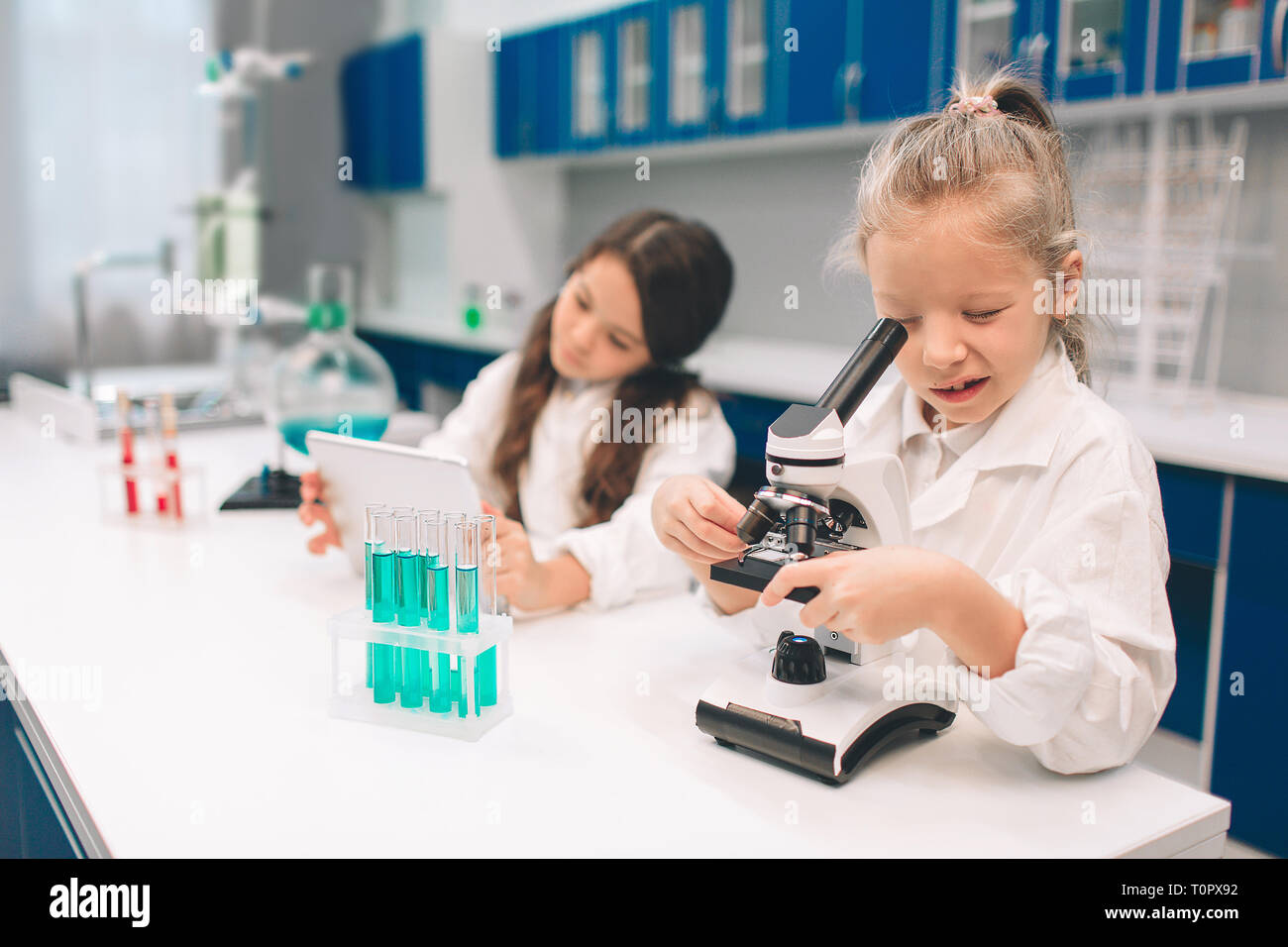 Two little kids in lab coat learning chemistry in school laboratory ...