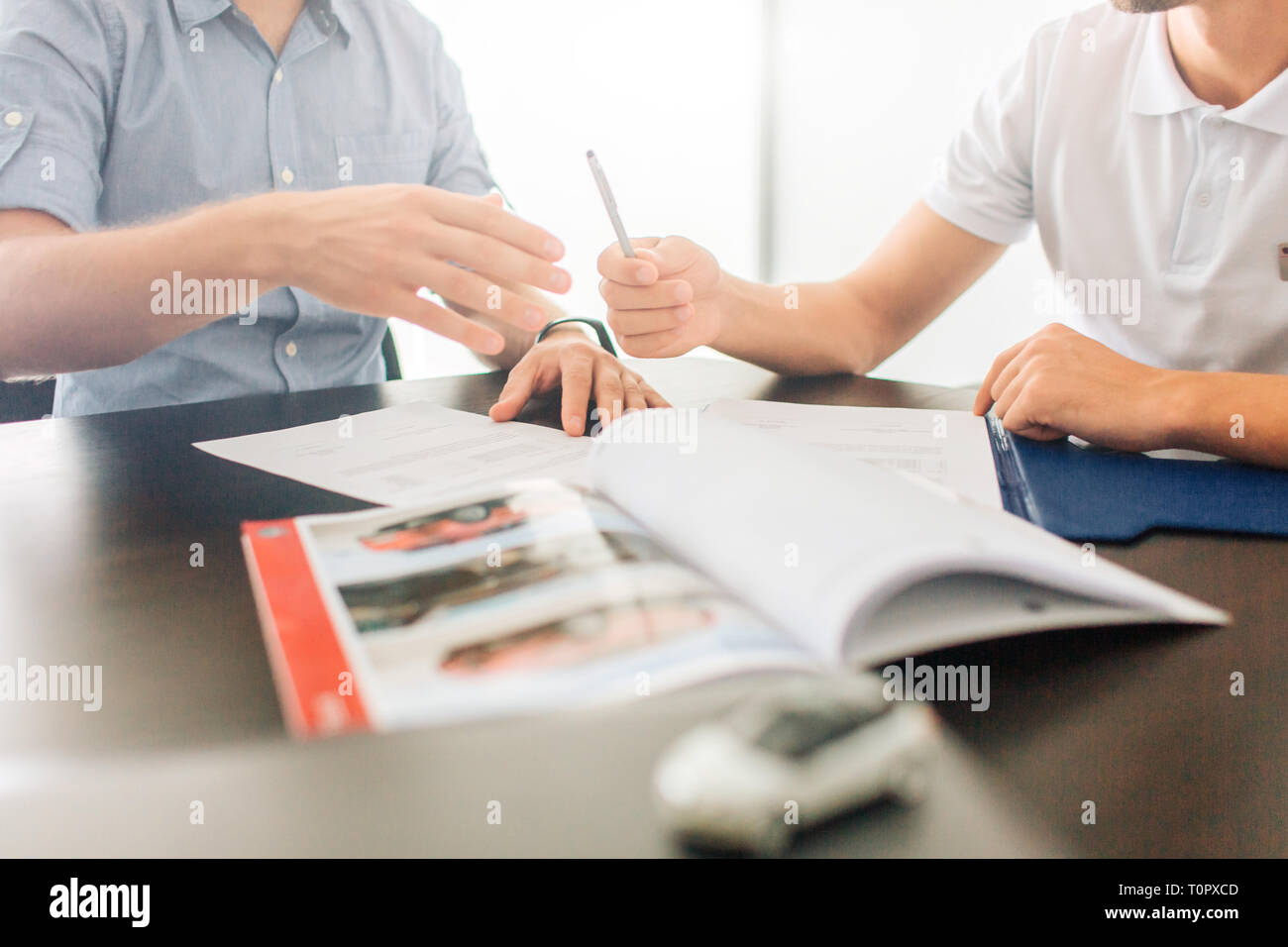 Picture of two men sit at table together. They hold hands on documents ...