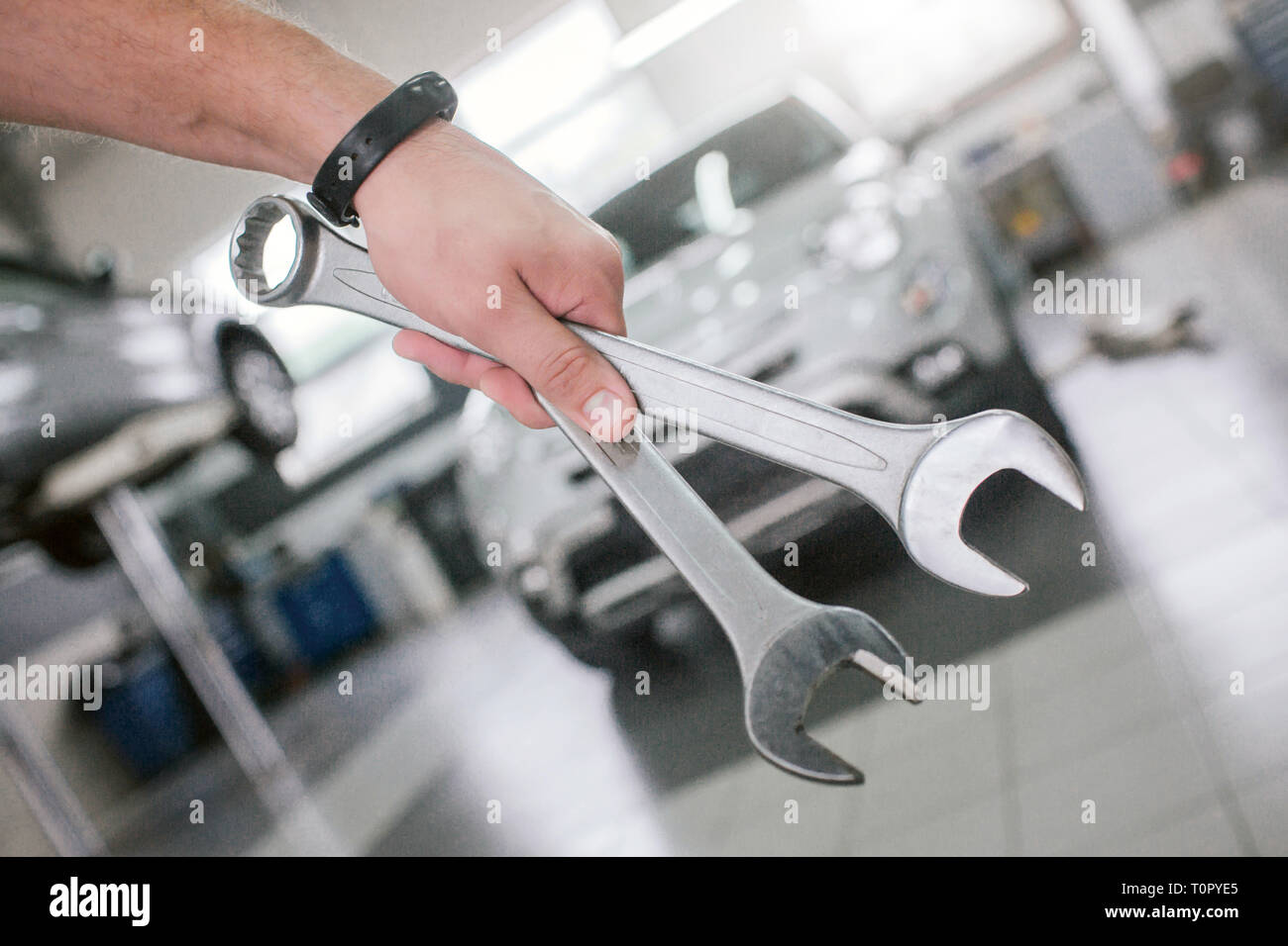 Cut view of strong man's hand holding two wrenches in front of white ...
