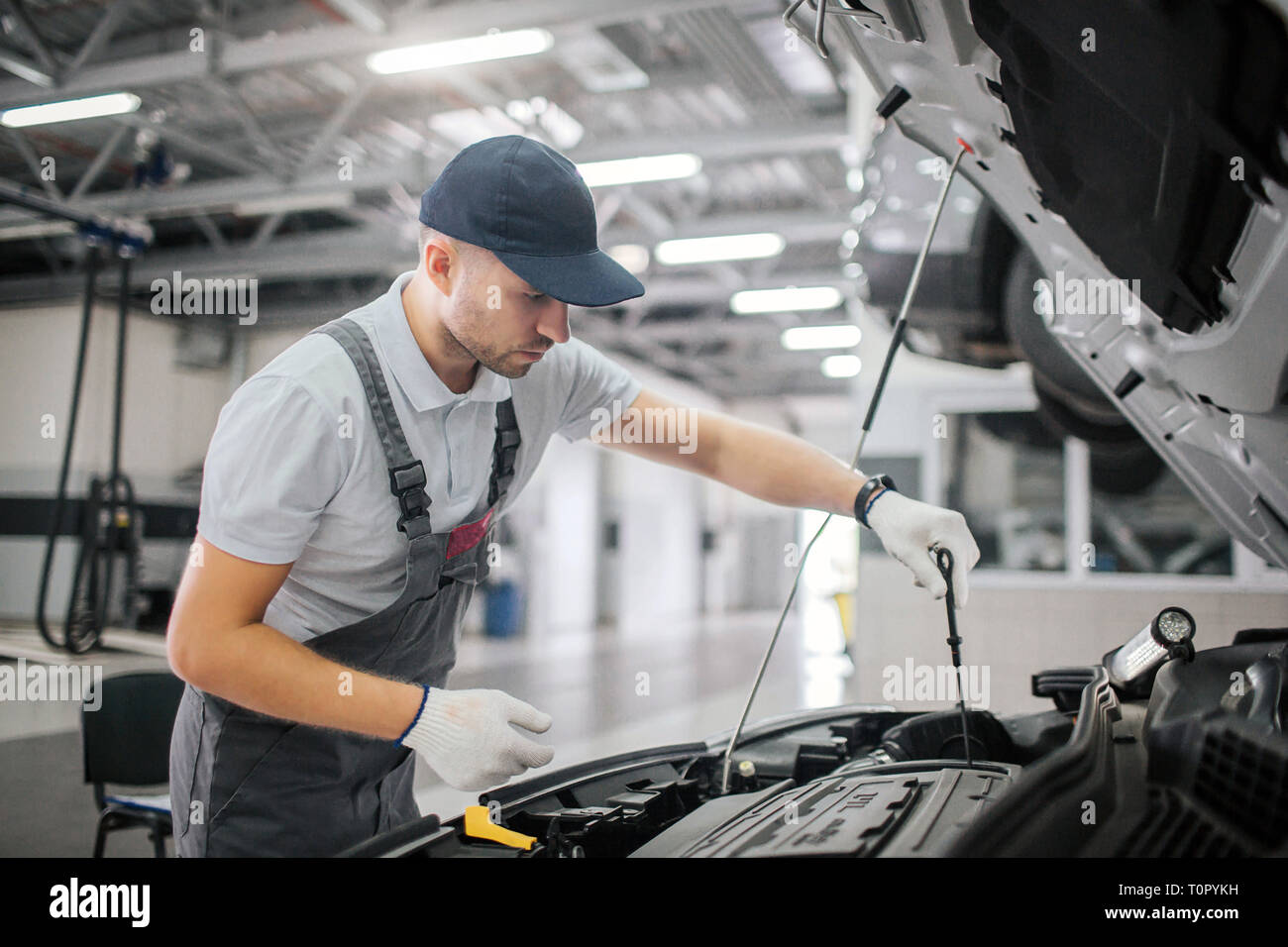 Man stands at opened body of car and works. He is serious and ...
