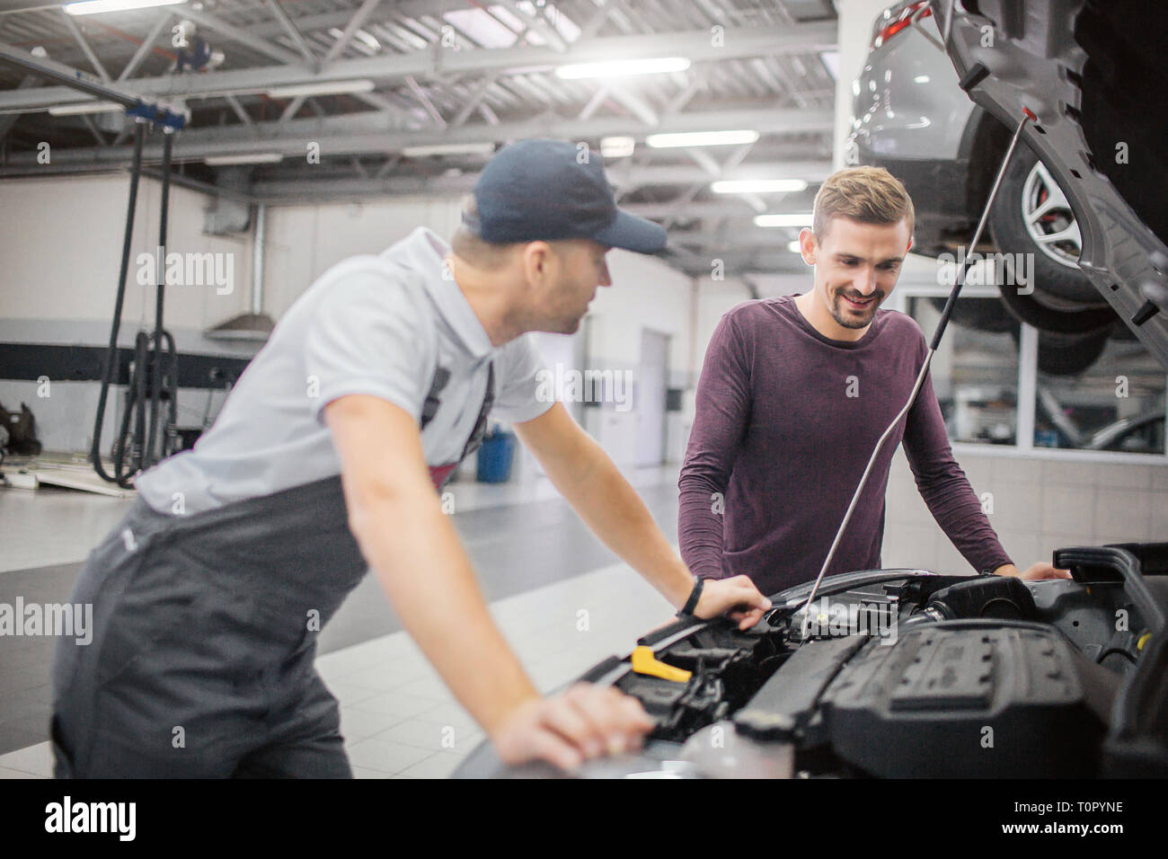 Worker and owner of car stand at opened front body of vehicle. Bearded ...