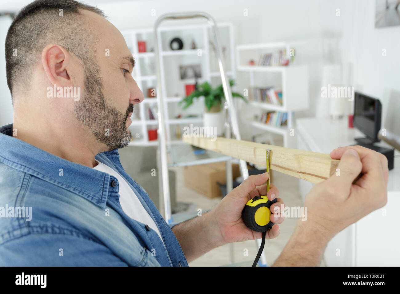 man measuring wood piece for furniture assembling Stock Photo - Alamy