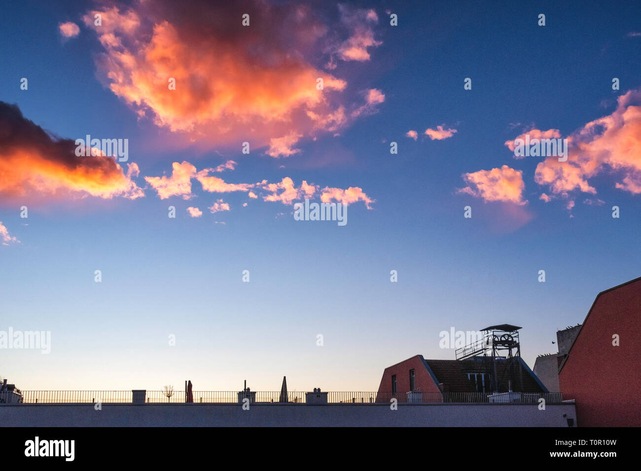 Pink clouds and blue sky over an apartment building rooftop at sunset ...