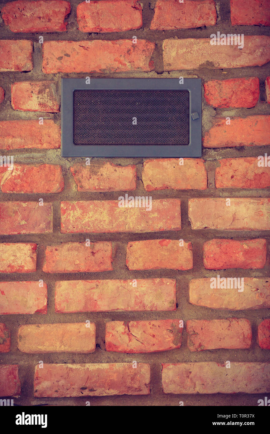 Textures and close up detailed patterns concept. Vent on red brick wall ...