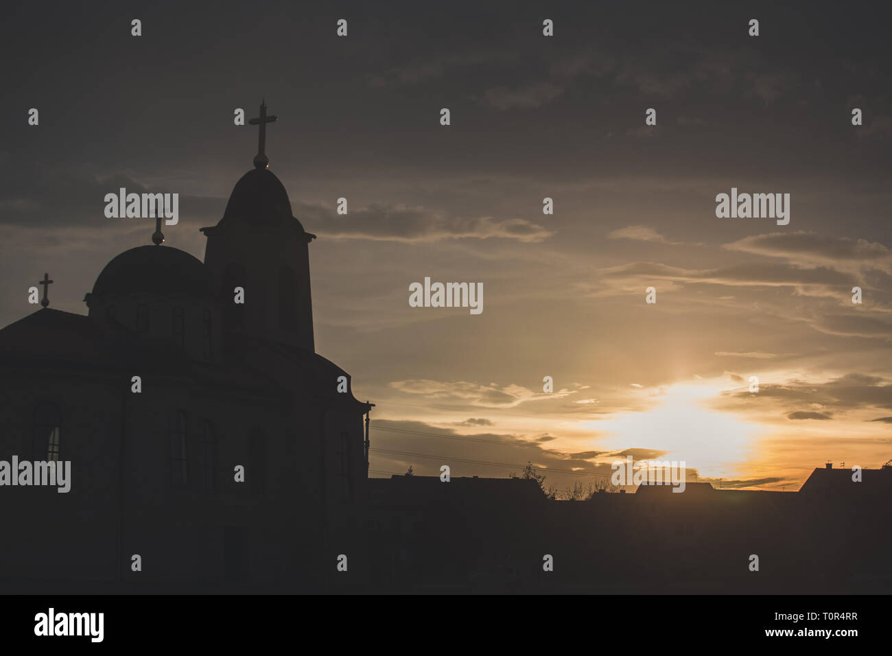 Orthodox church silhouette at sunset with cloudy sky and sun in ...