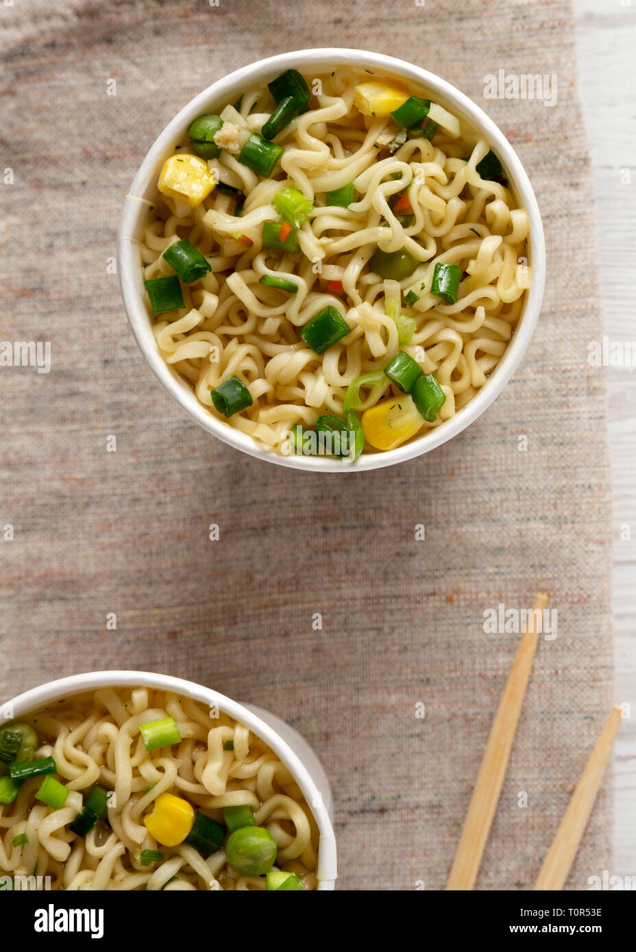 Tasty instant ramen noodles with beef flavoring in paper cups. Flat lay ...