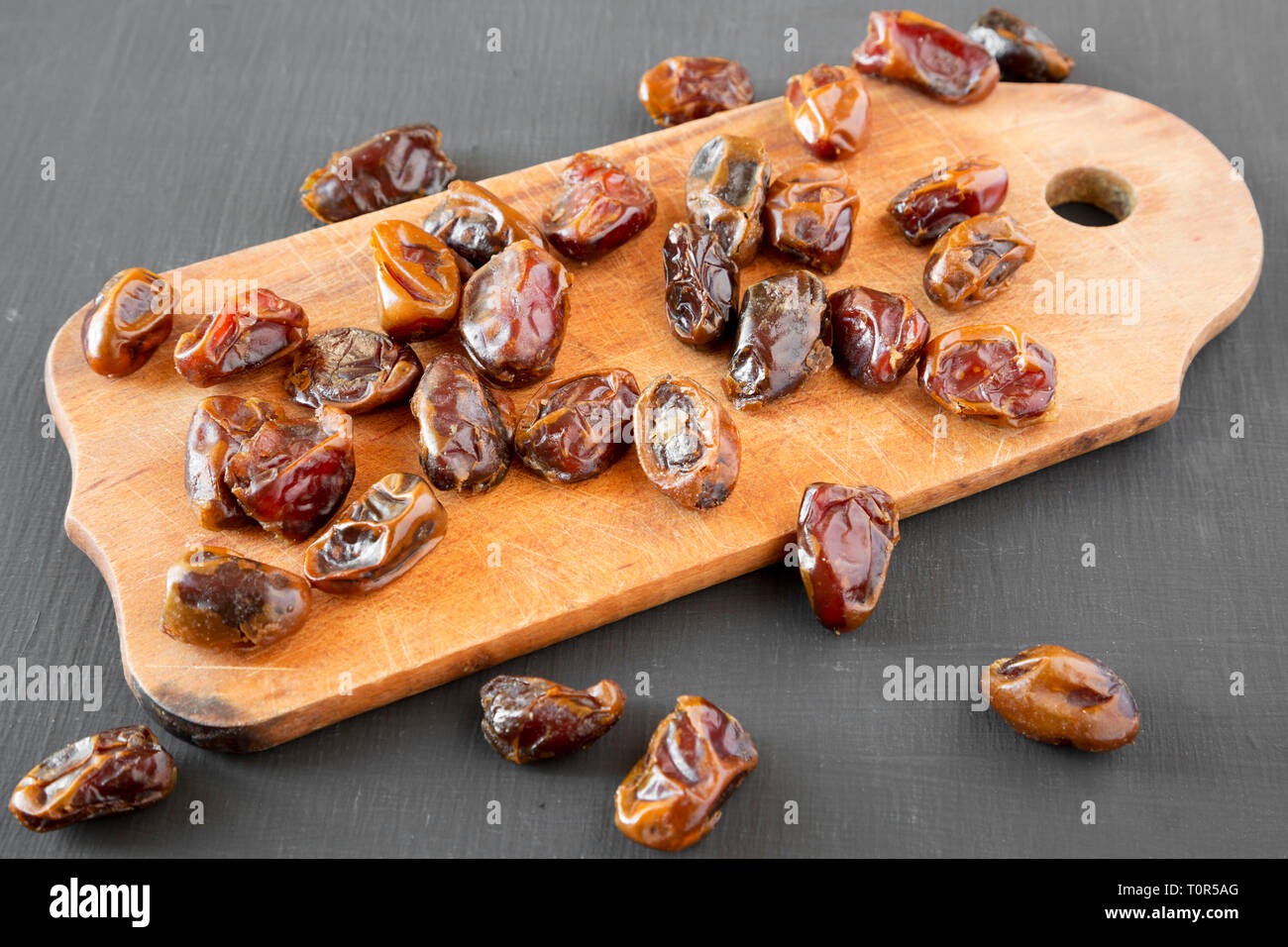 Dried dates on rustic wooden board over black background, side view ...