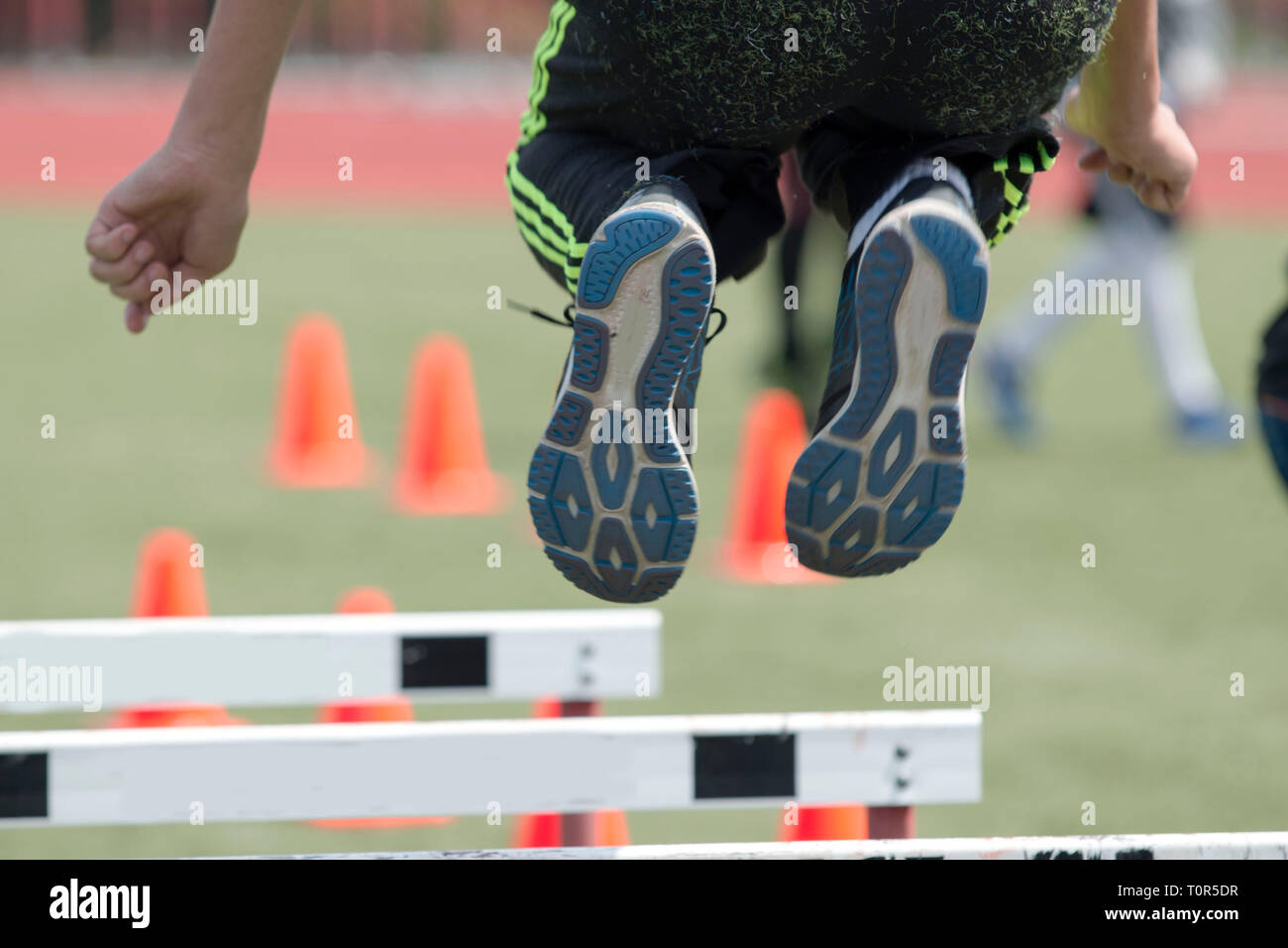 A high school athlete jumping over hurdles for strength work Stock ...
