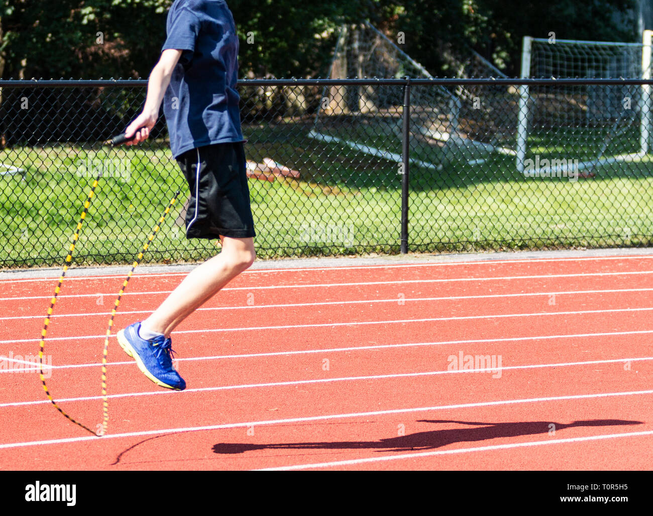 A high school runner is cross training by jumping rope on a track in ...