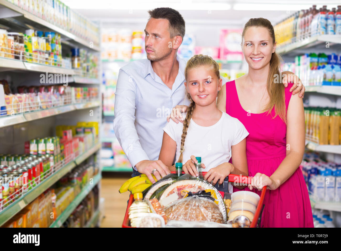 Positive family customers smiling and standing with purchases in ...