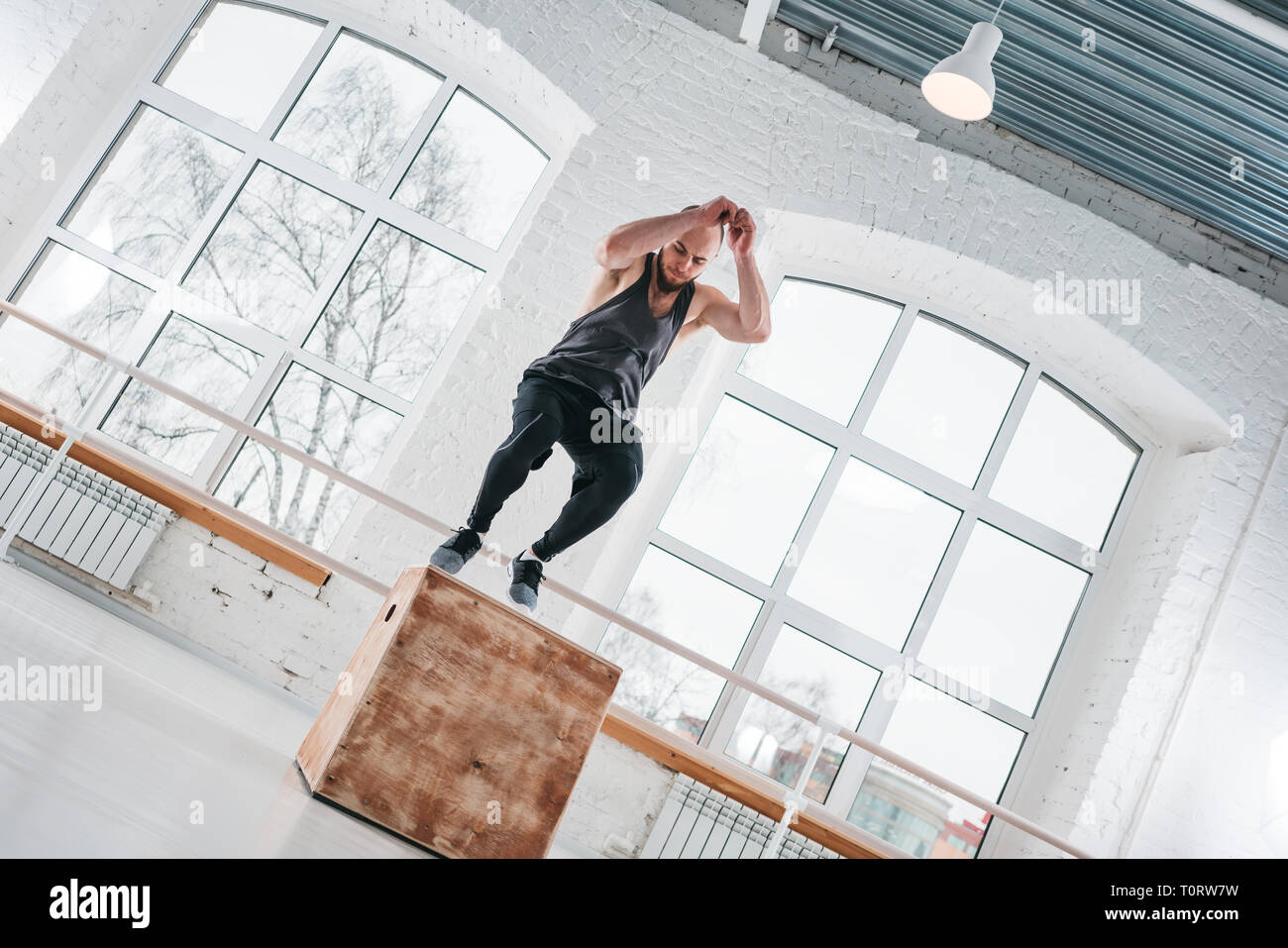 Strong man doing a box jump exercise at workout gym. Male athlete using ...