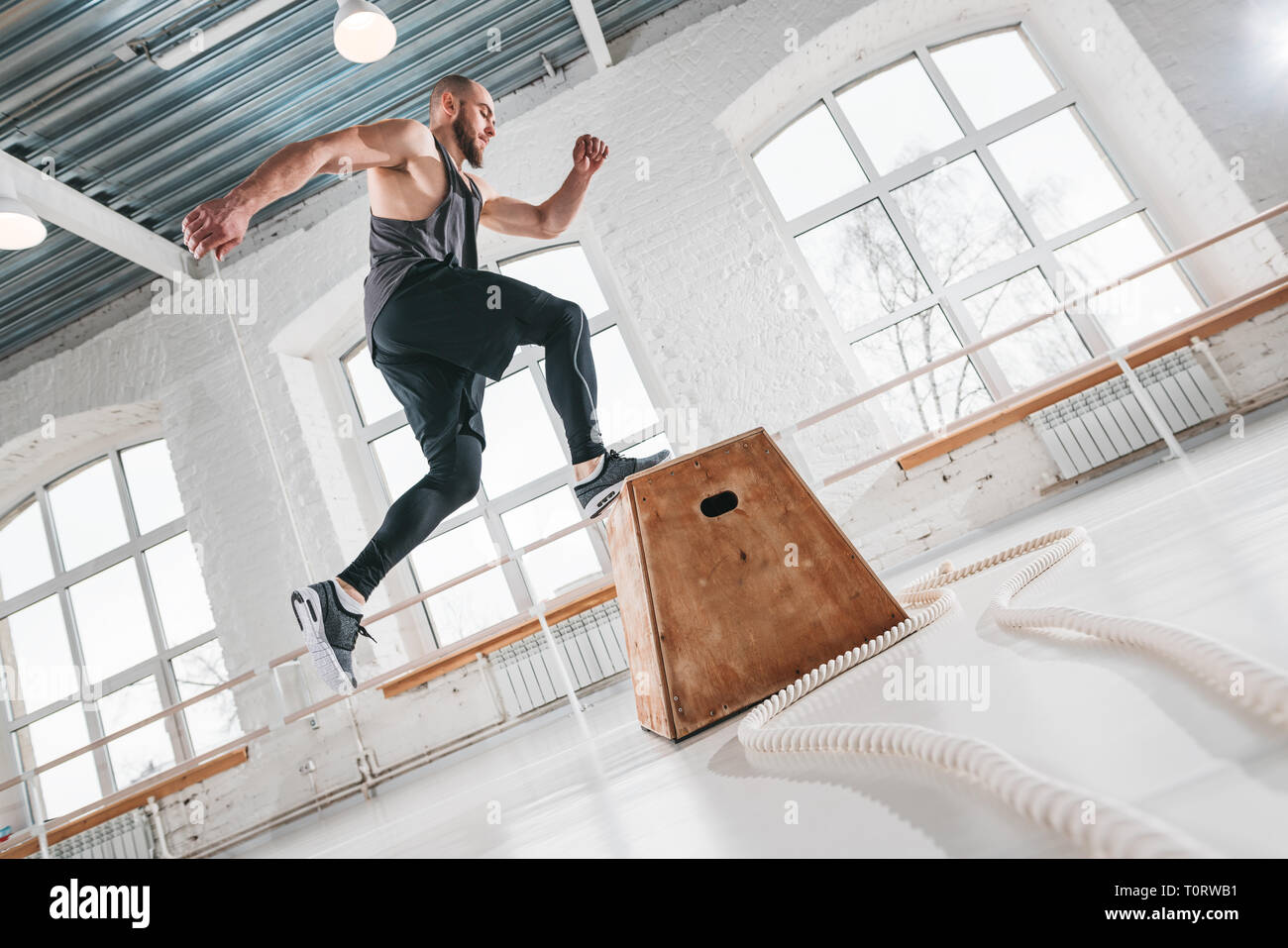 Strong man doing a box jump exercise at workout gym. Male athlete using ...