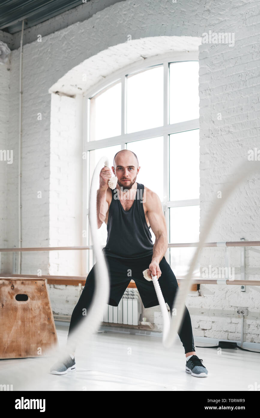 Strong man using battle ropes for cross exercising. Muscular male ...