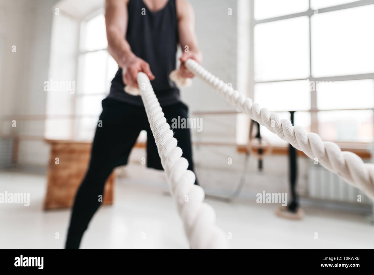 Muscular male athlete doing exercises with rope at gym. Fitness man ...