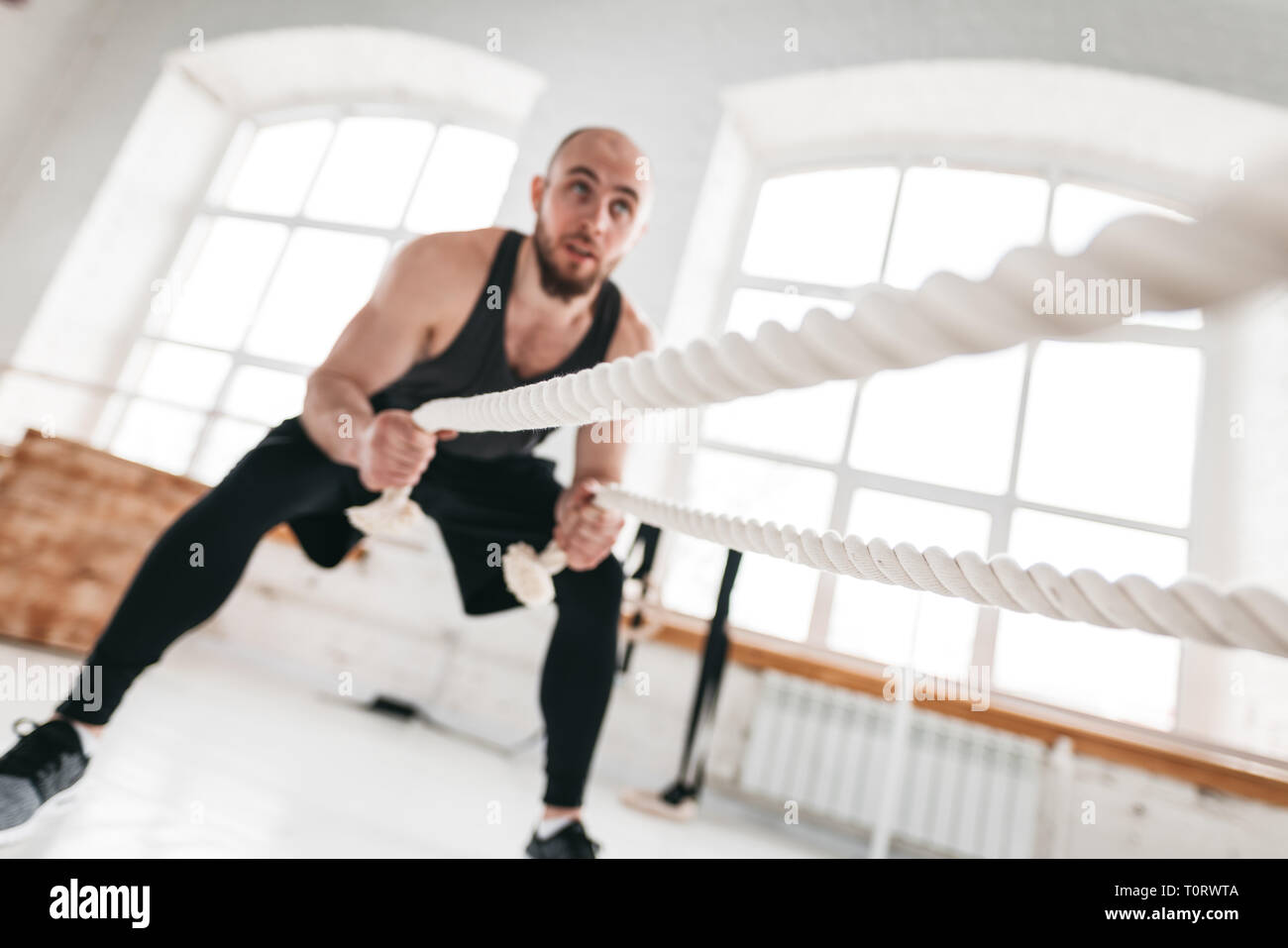 Strong male athlete doing exercises with rope at gym. working out with ...