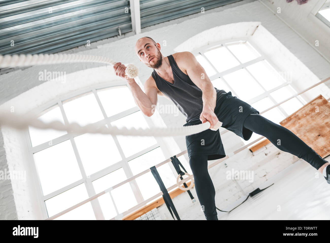 Fit man working out with battle ropes at hall. Male athlete training ...