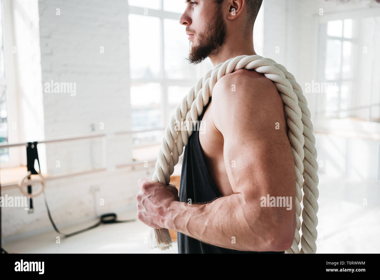 Strong male athlete holding on shoulder rope after intense workout ...