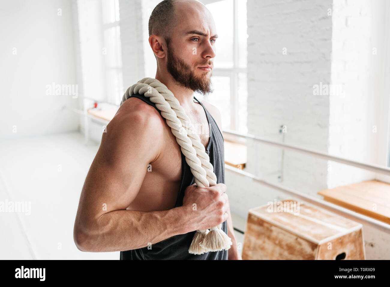 Strong male athlete holding on shoulder rope after intense workout ...