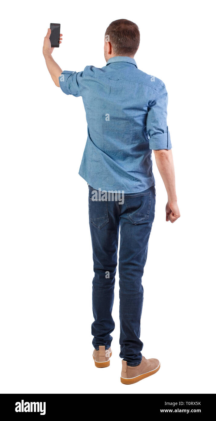 Back view of man who makes selfie with a smartphone. guy watching. Rear ...