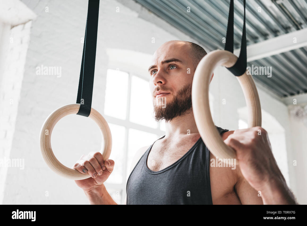 Strong bearded man holding gymnastic rings at gym. Exercising male ...