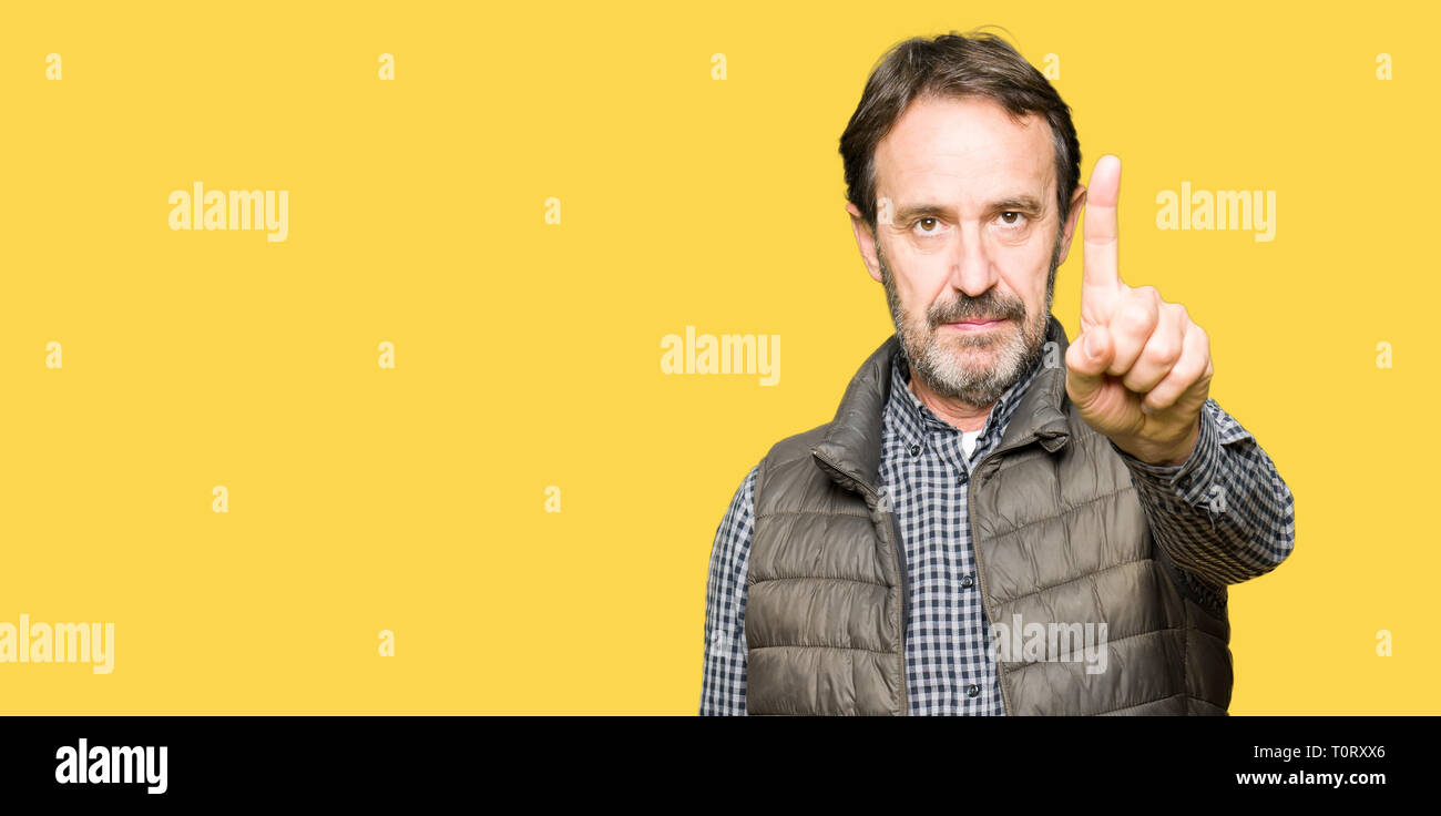 Middle age handsome man wearing winter vest Pointing with finger up and ...