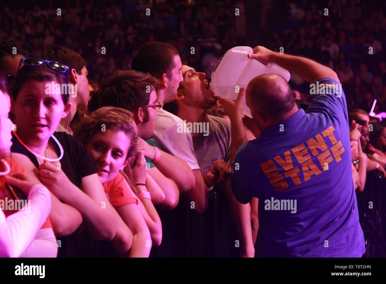 A front row concert fan is shown receiving an H2O pour from a security ...